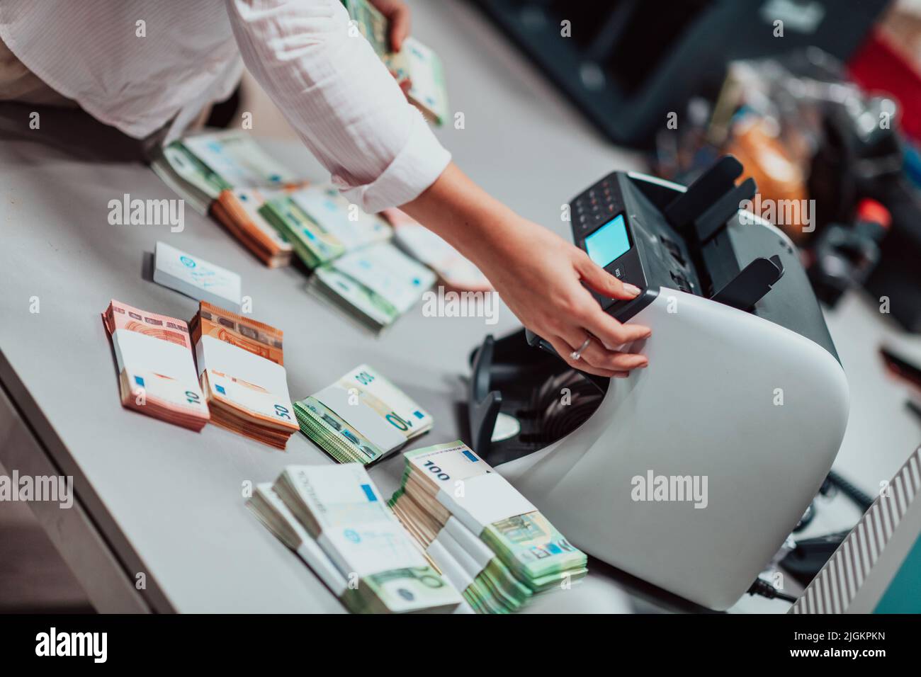 Bank employees using money counting machine while sorting and counting ...
