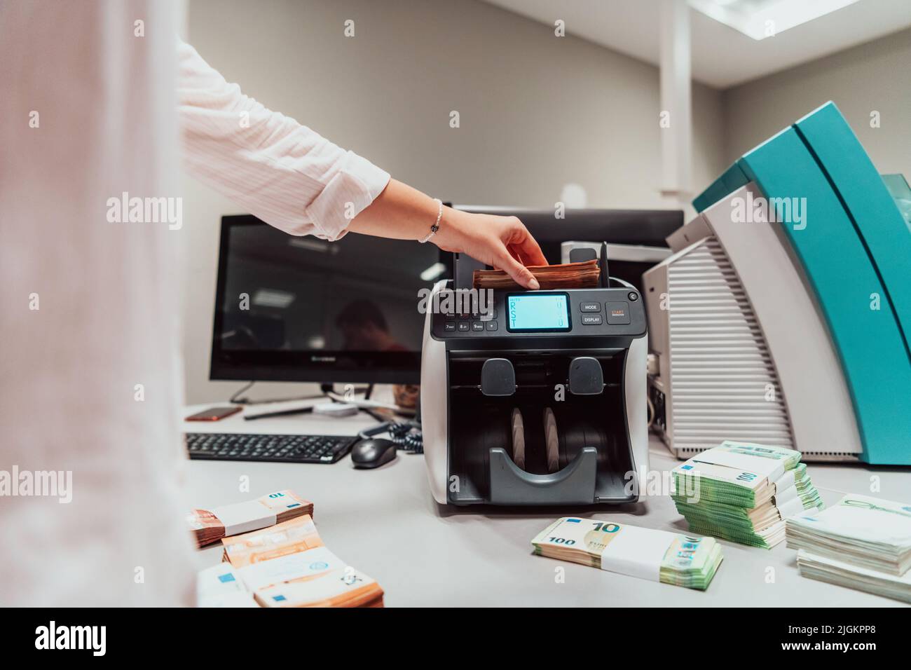 Bank employees using money counting machine while sorting and counting ...