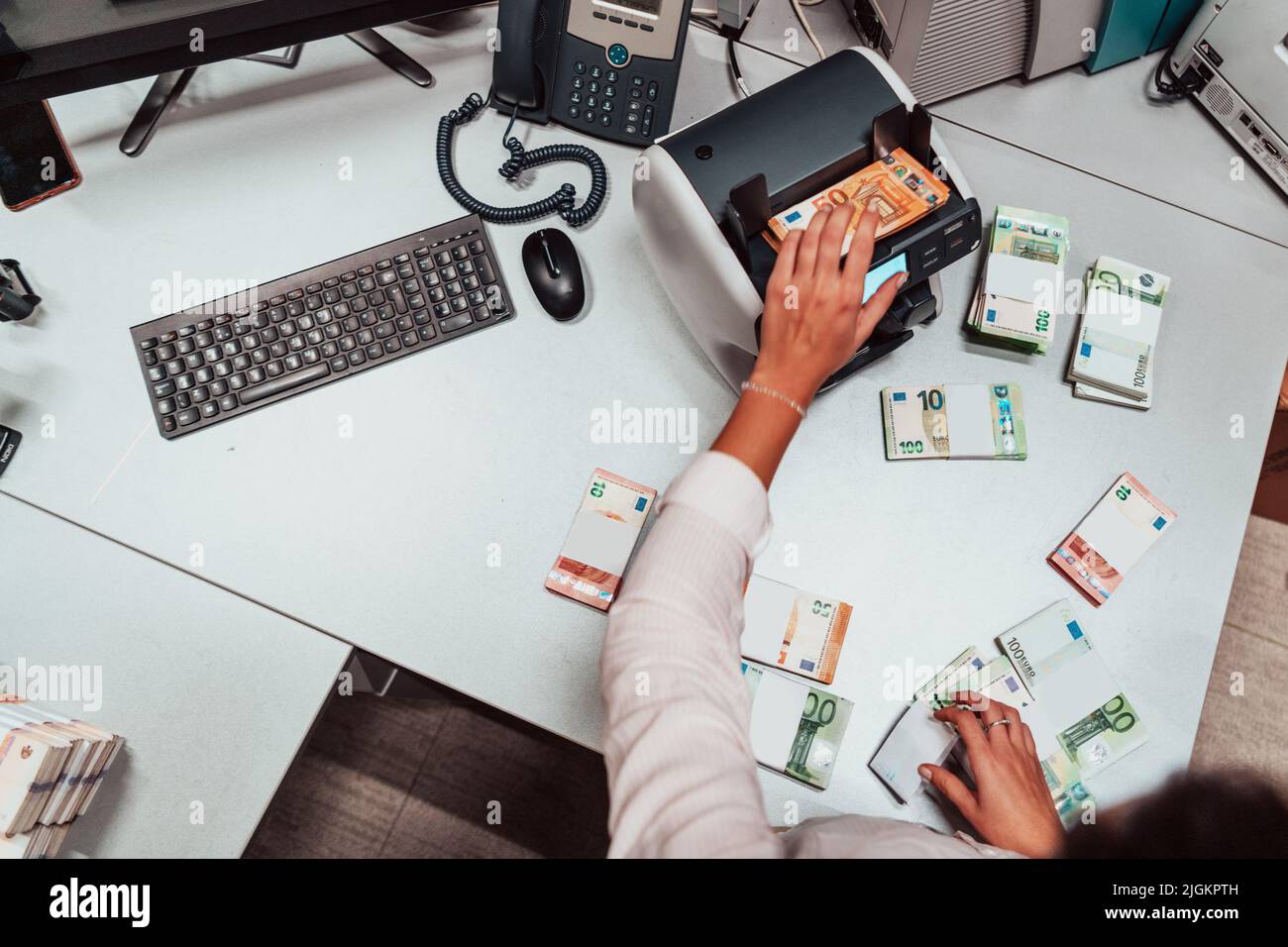 Bank employees using money counting machine while sorting and counting ...