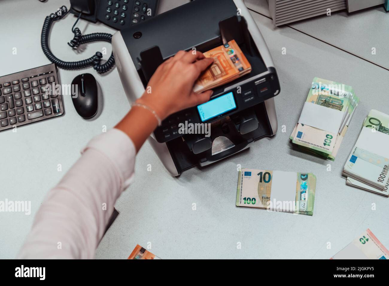 Bank employees using money counting machine while sorting and counting ...