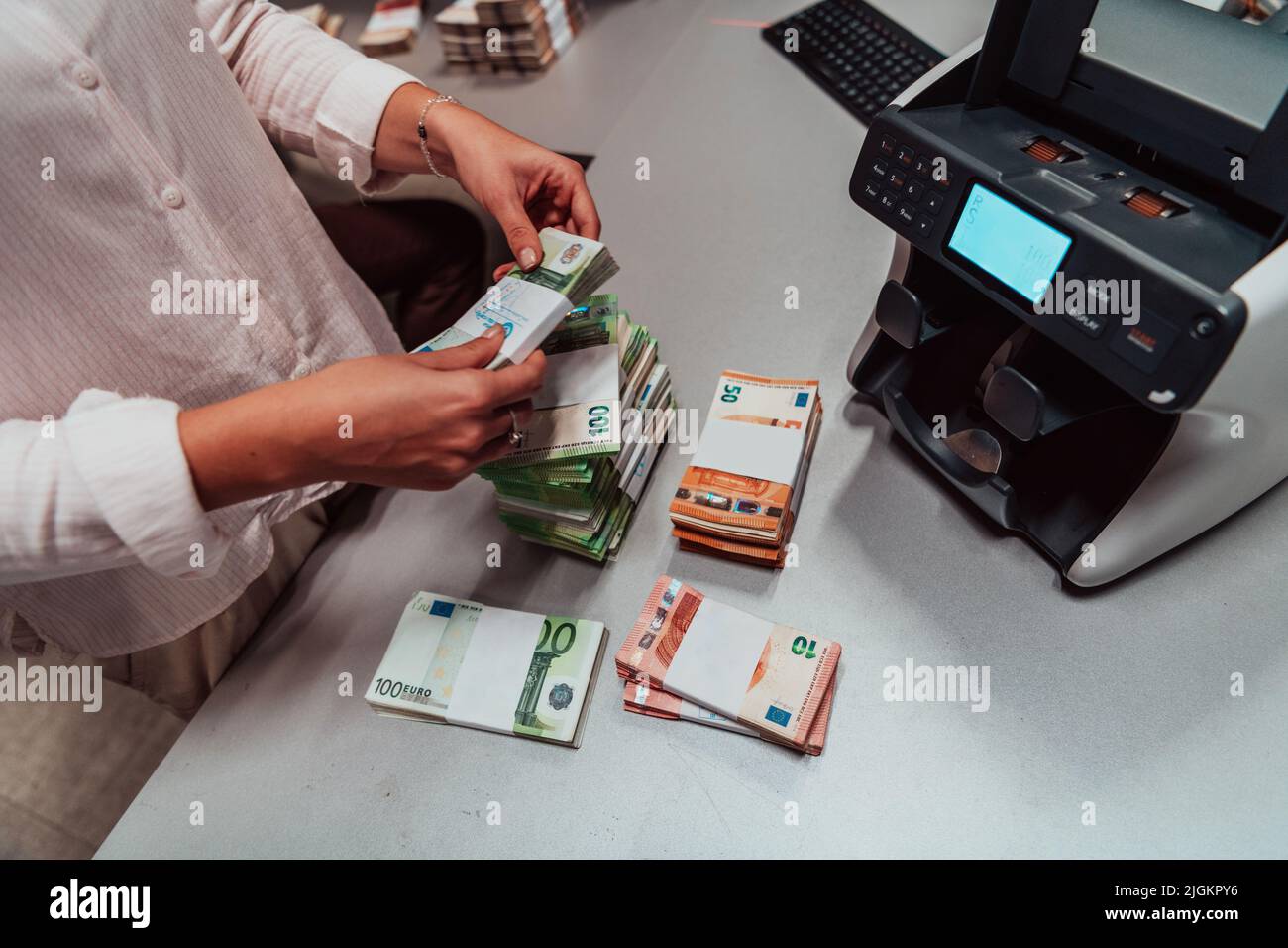 Bank employees using money counting machine while sorting and counting ...