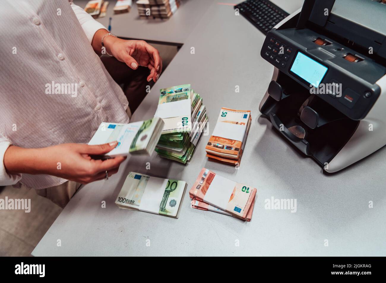 Bank employees using money counting machine while sorting and counting ...