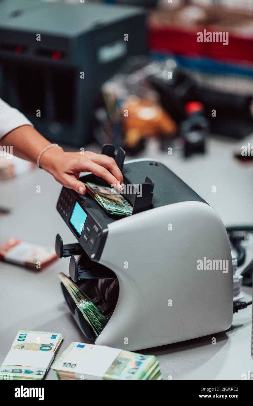 Bank employees using money counting machine while sorting and counting ...