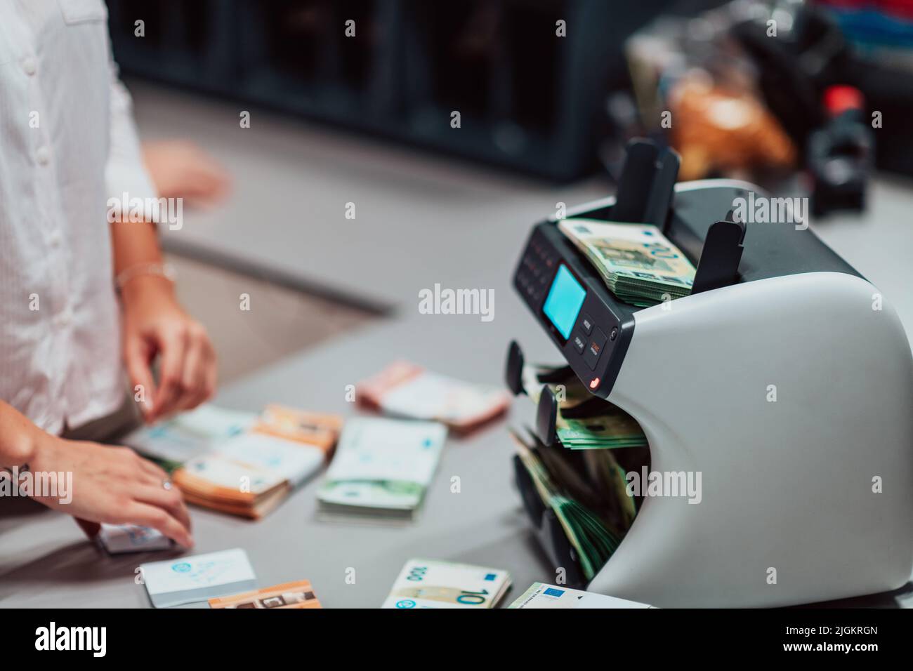 Bank employees using money counting machine while sorting and counting ...
