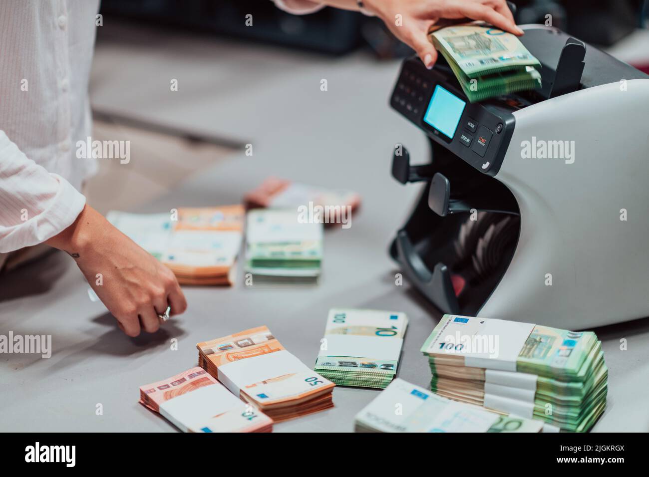 Bank employees using money counting machine while sorting and counting ...