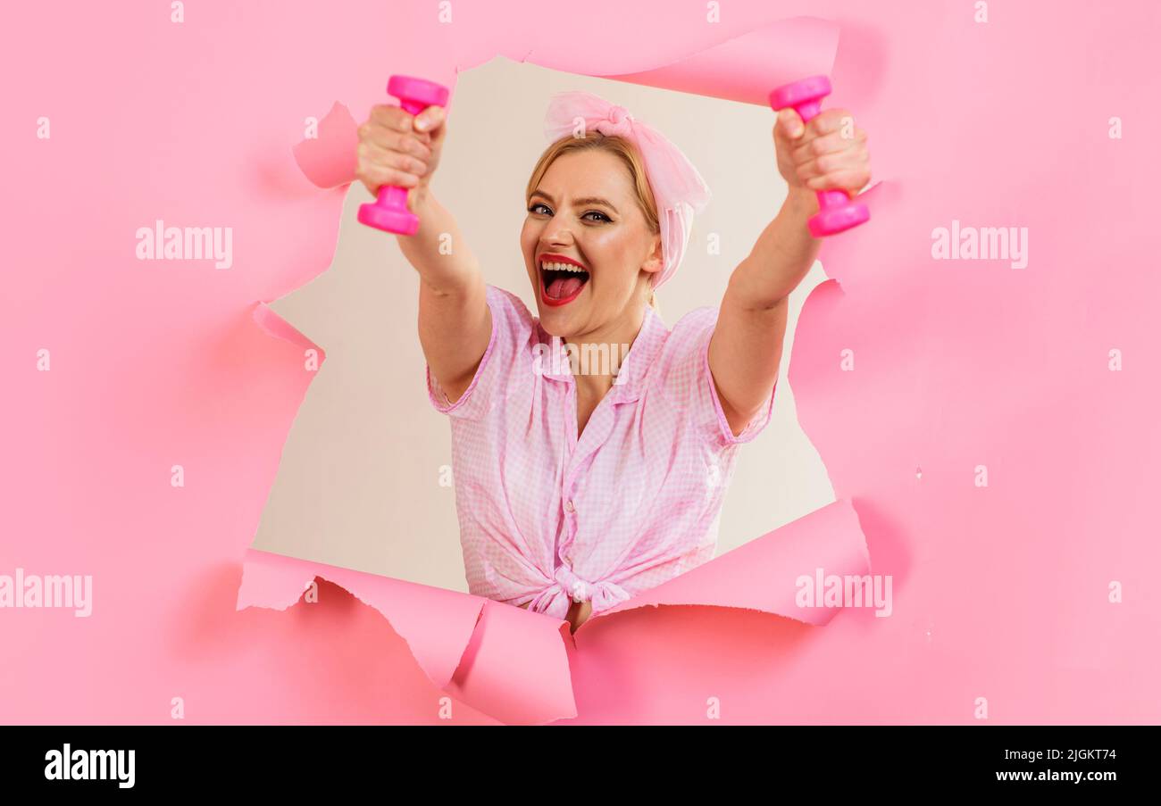 Happy woman with dumbbells looking through paper hole. Smiling girl ...