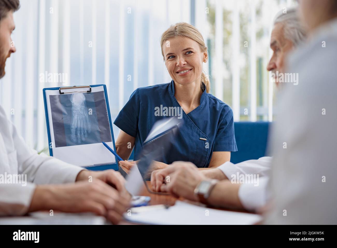 Group of doctors sitting at meeting table in conference room during ...