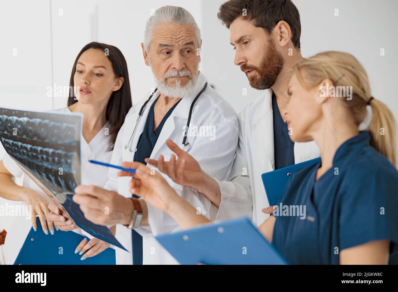 Group of doctors in uniform look and discuss an X-ray or MRI scan of ...