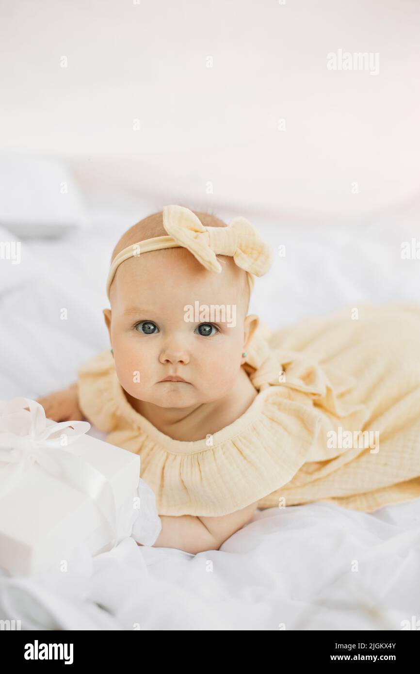 Happy caucasian little baby girl lying on bed looking at camera and smiling in bedroom at home ...