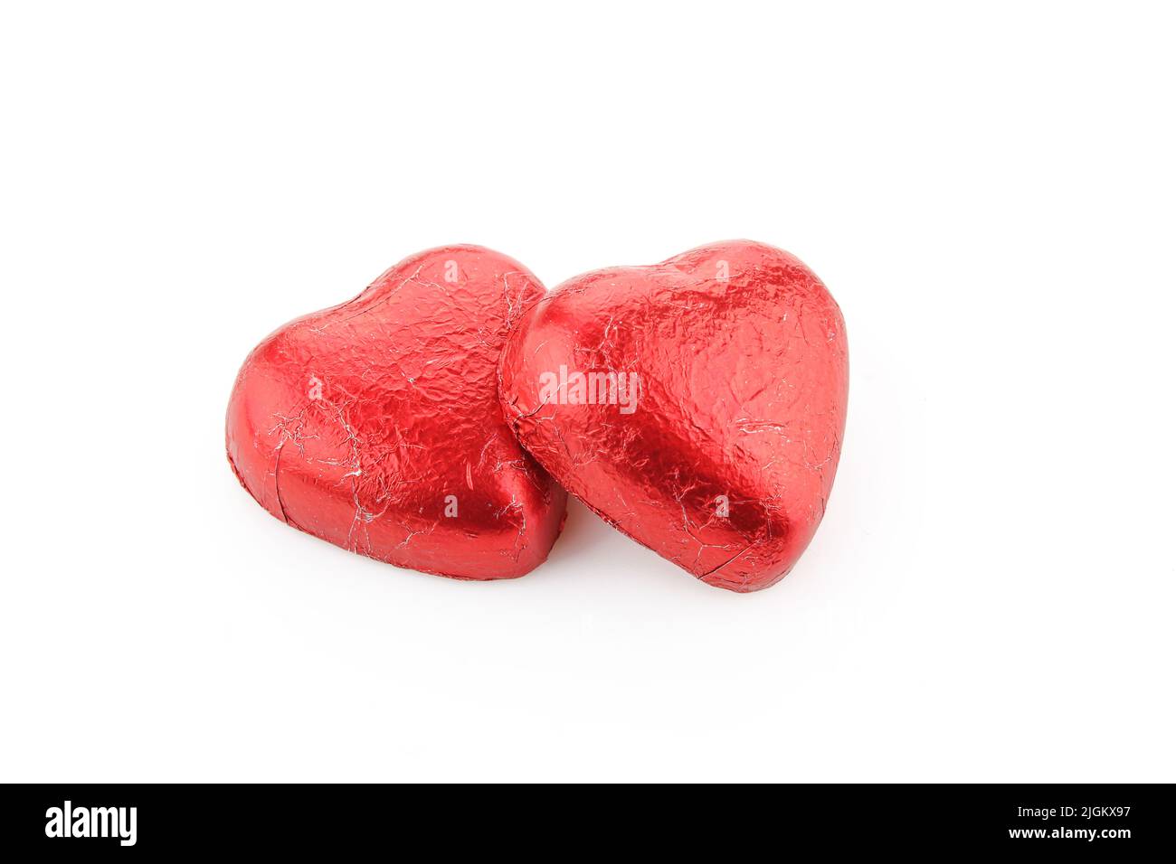 Pair of heart shaped chocolate candies wrapped in red foil isolated on ...