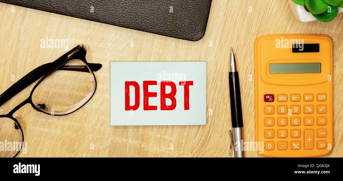 debt.The word is written on a slip of paper,on colored background ...