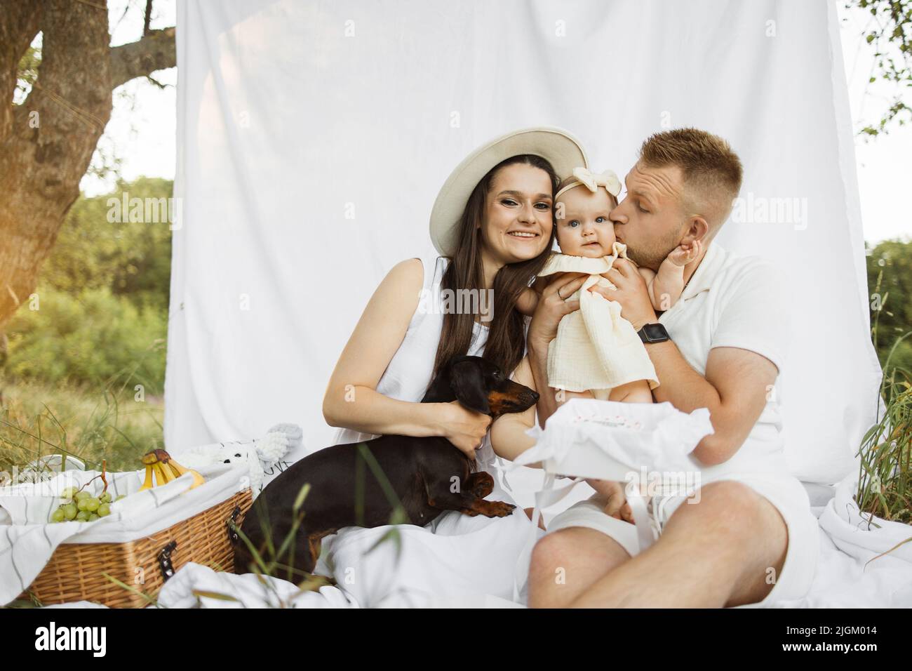Portrait of smiling young parents embarrassing their little daughter ...