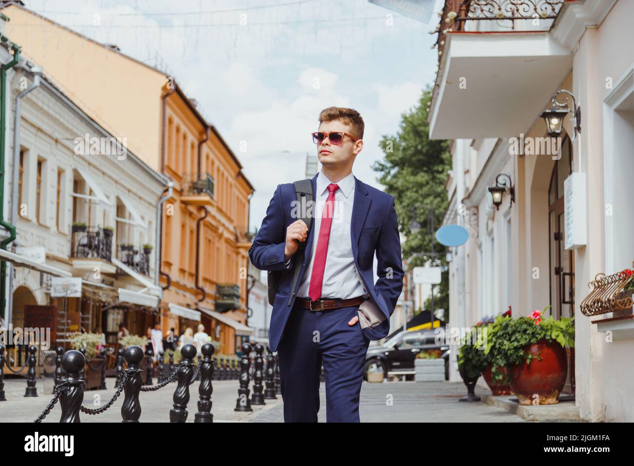 Young handsome man in suit with sunglasses and backpack. White collar ...