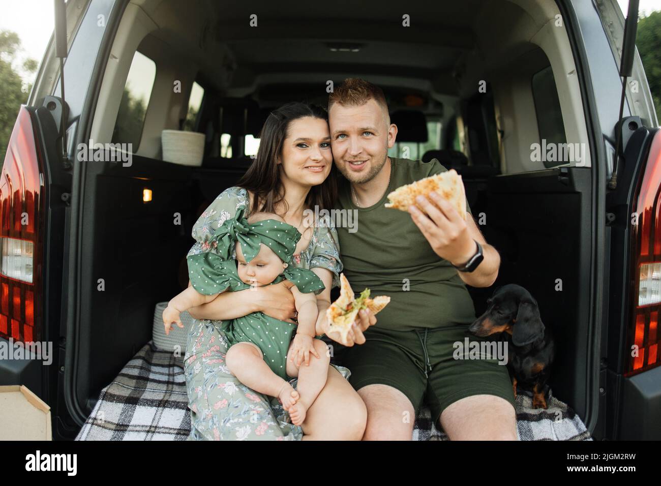 Beautiful married couple with daughter looking at camera while sitting ...