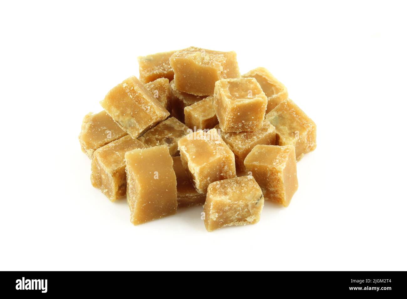 Pile of brown sugar cubes isolated on white background. Walnut and milk ...