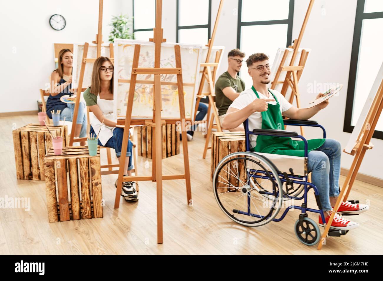 Young disabled man sitting on wheelchair drawing at art studio smiling ...