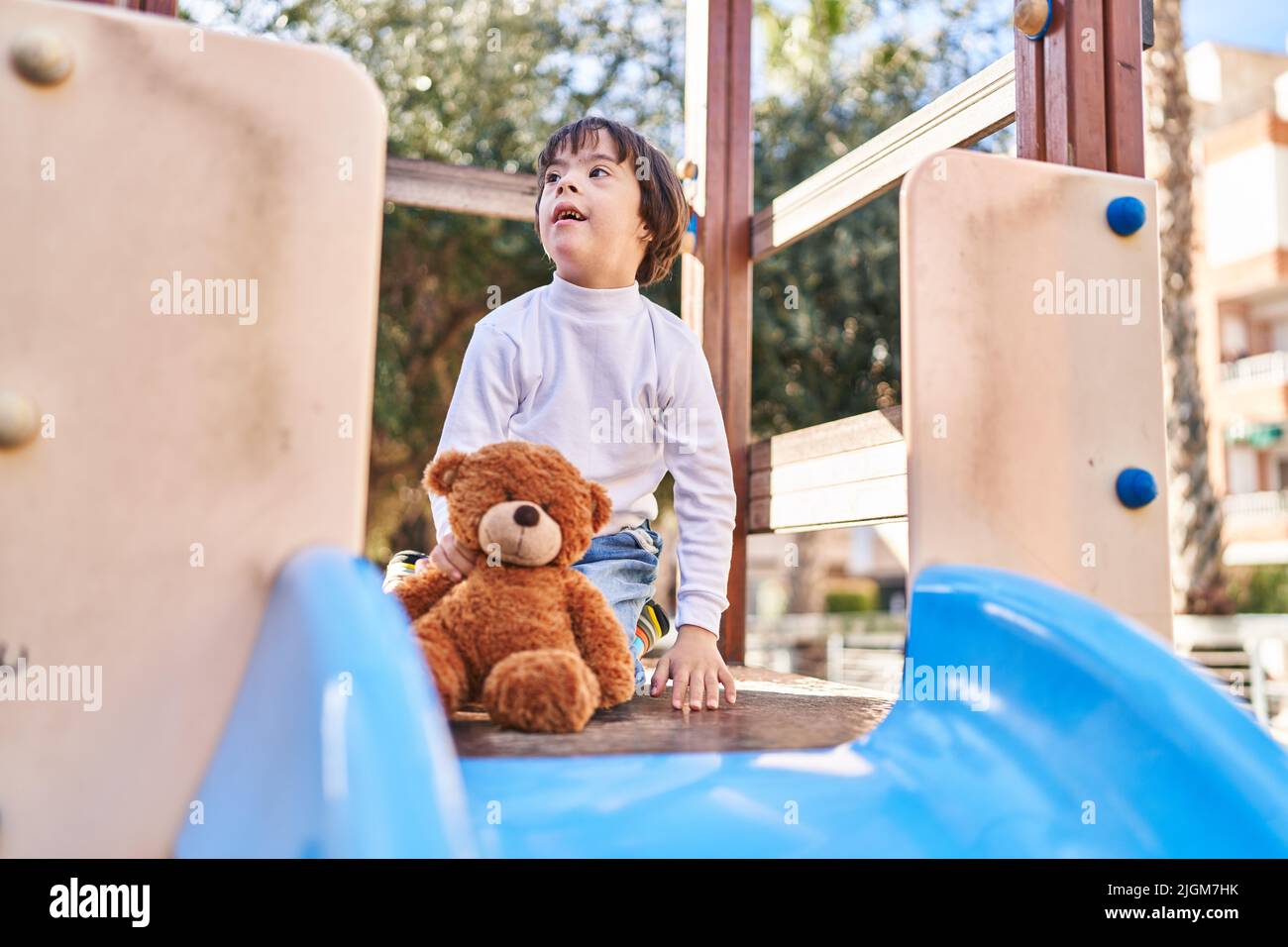 Down syndrome kid smiling confident playing with teddy bear on slide at park Stock Photo - Alamy
