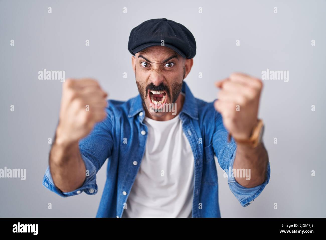 Hispanic man with beard standing over isolated background angry and mad ...