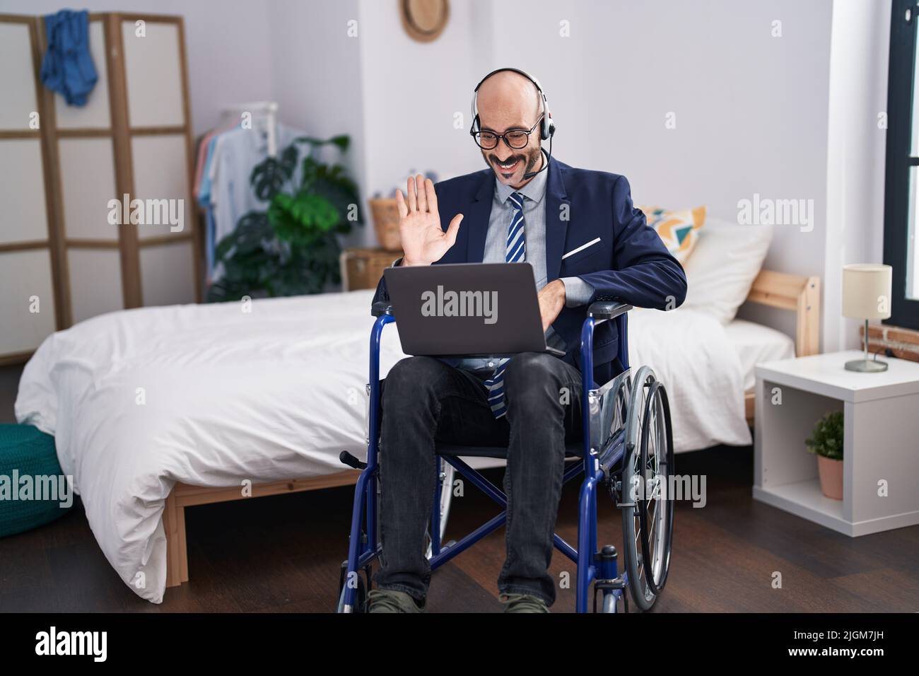 Hispanic man with beard sitting on wheelchair doing business video call ...
