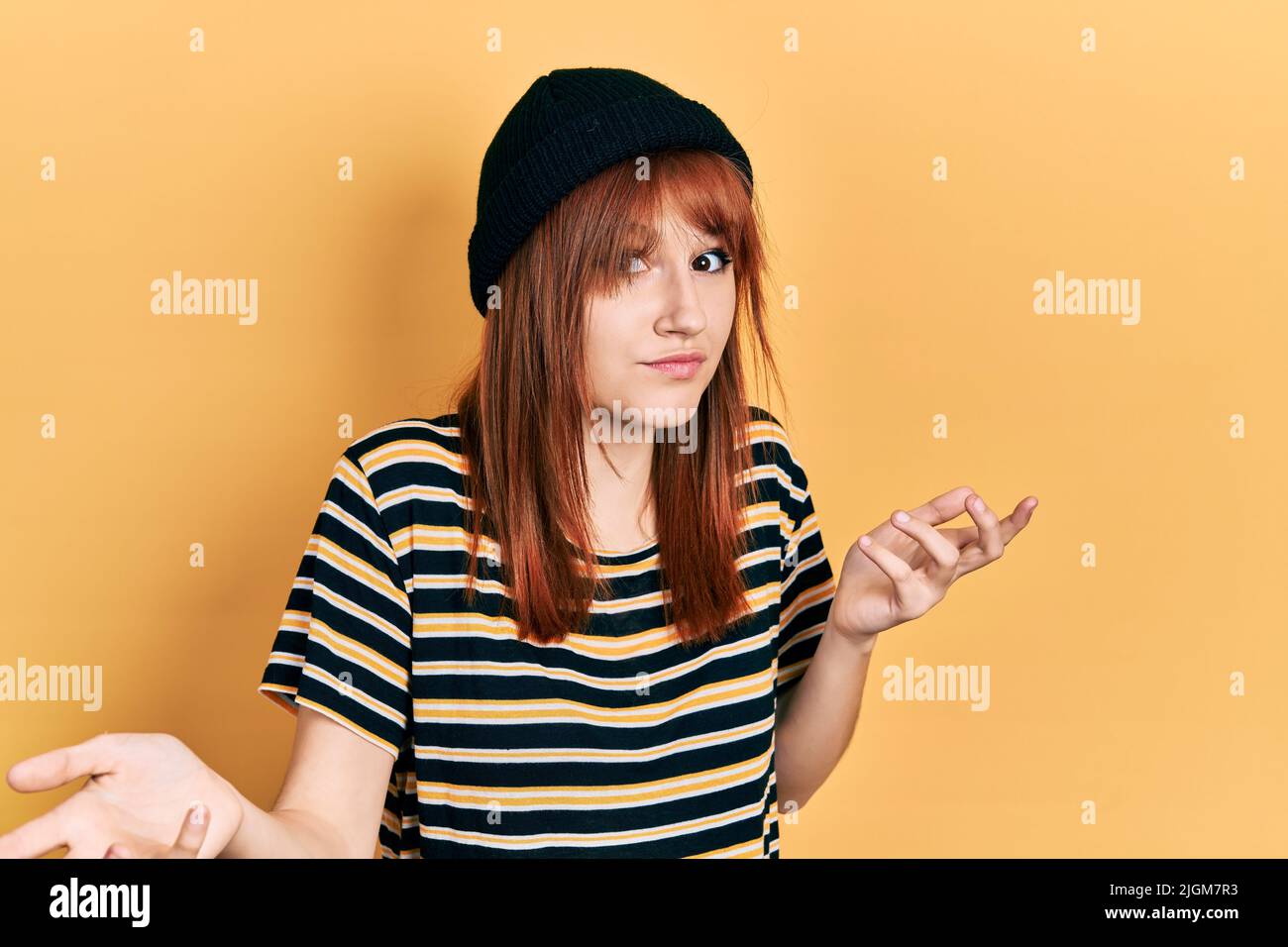 Redhead young woman wearing wool cap clueless and confused expression ...