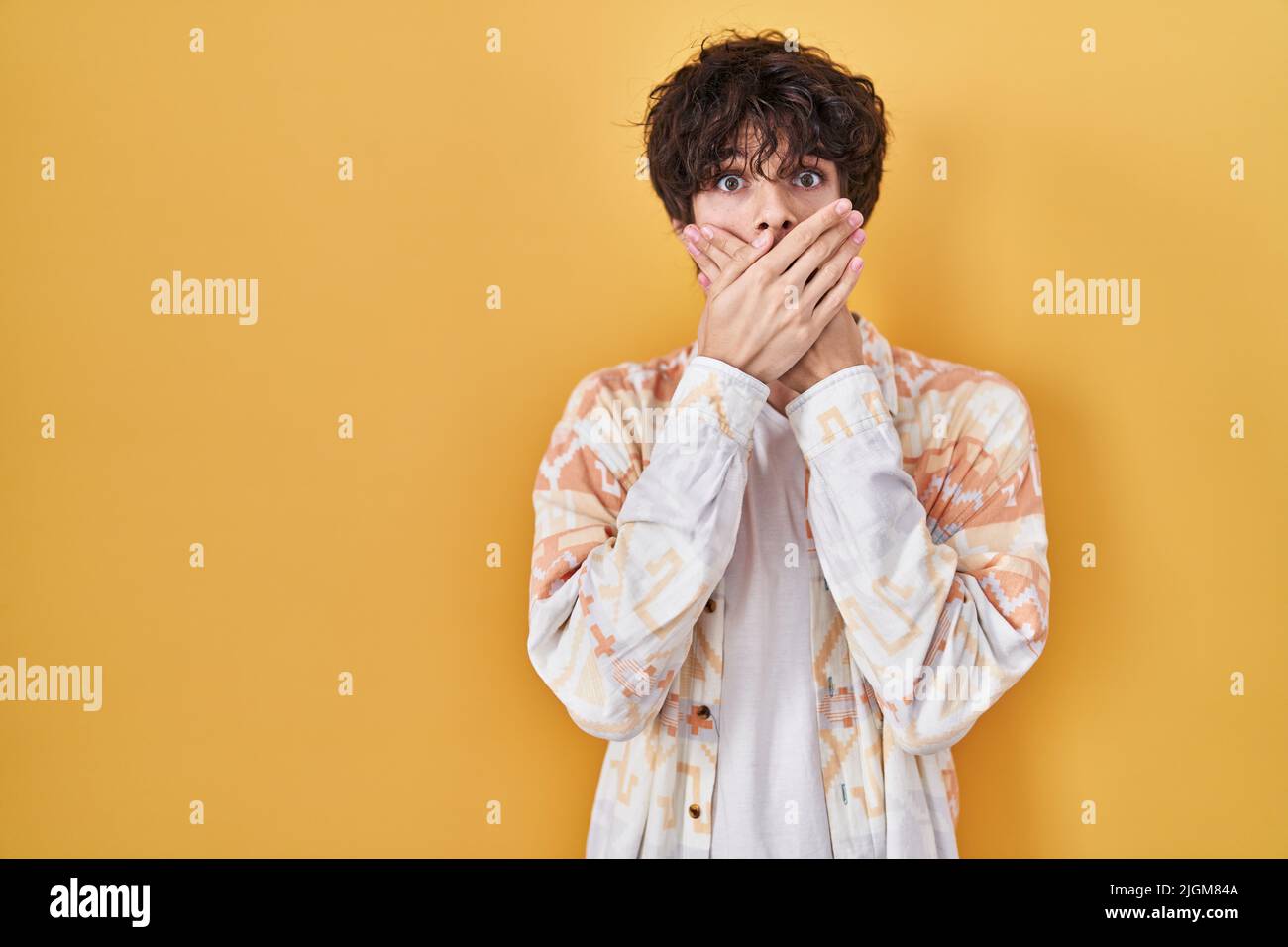 Young man wearing casual summer shirt shocked covering mouth with hands ...
