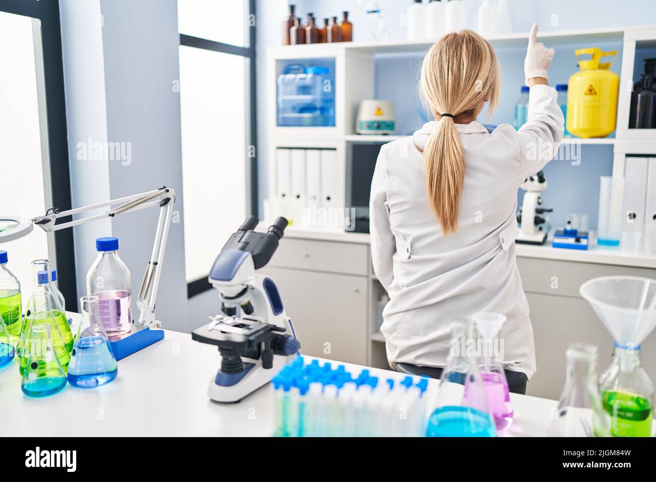 Middle age blonde woman working at scientist laboratory posing ...
