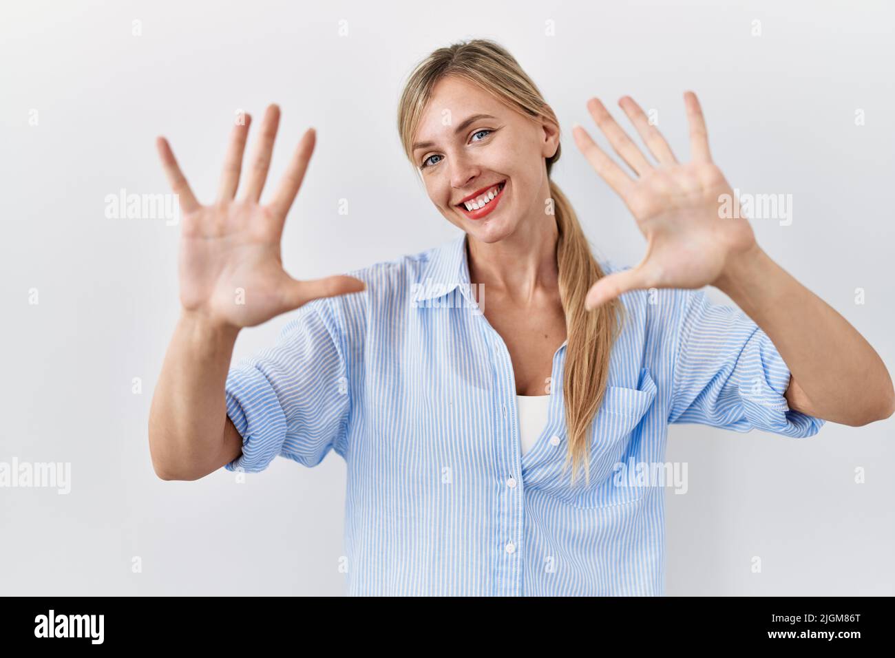 Beautiful blonde woman standing over white background showing and ...