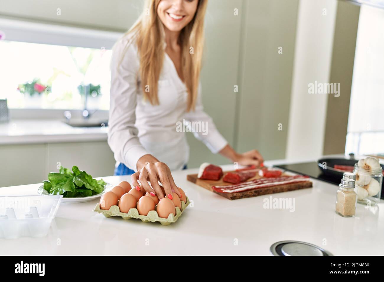 Young blonde woman smiling confident cooking beef at kitchen Stock ...