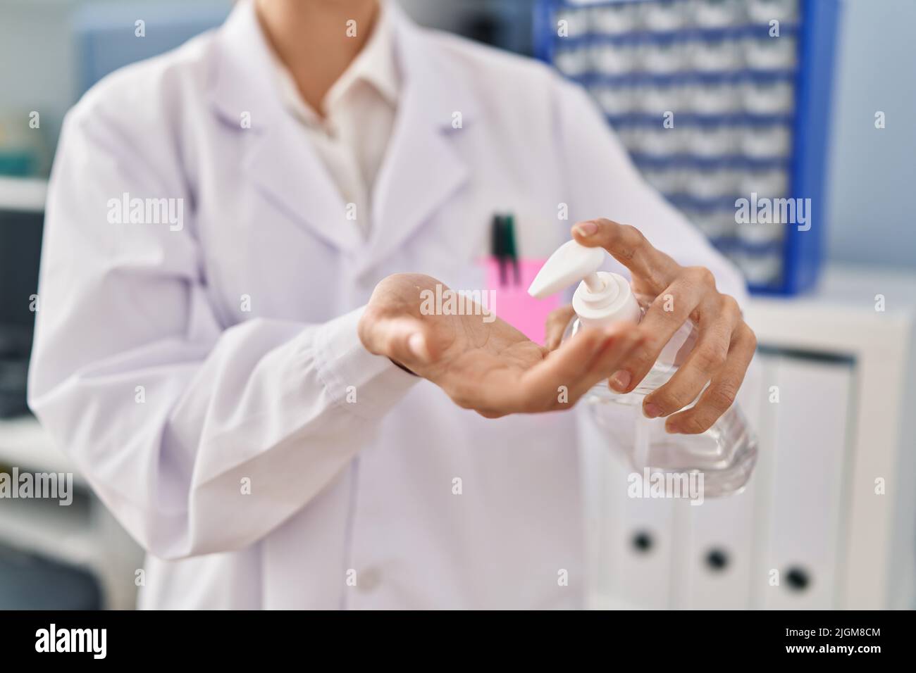 Young woman wearing scientist uniform using sanitizer hands gel at ...