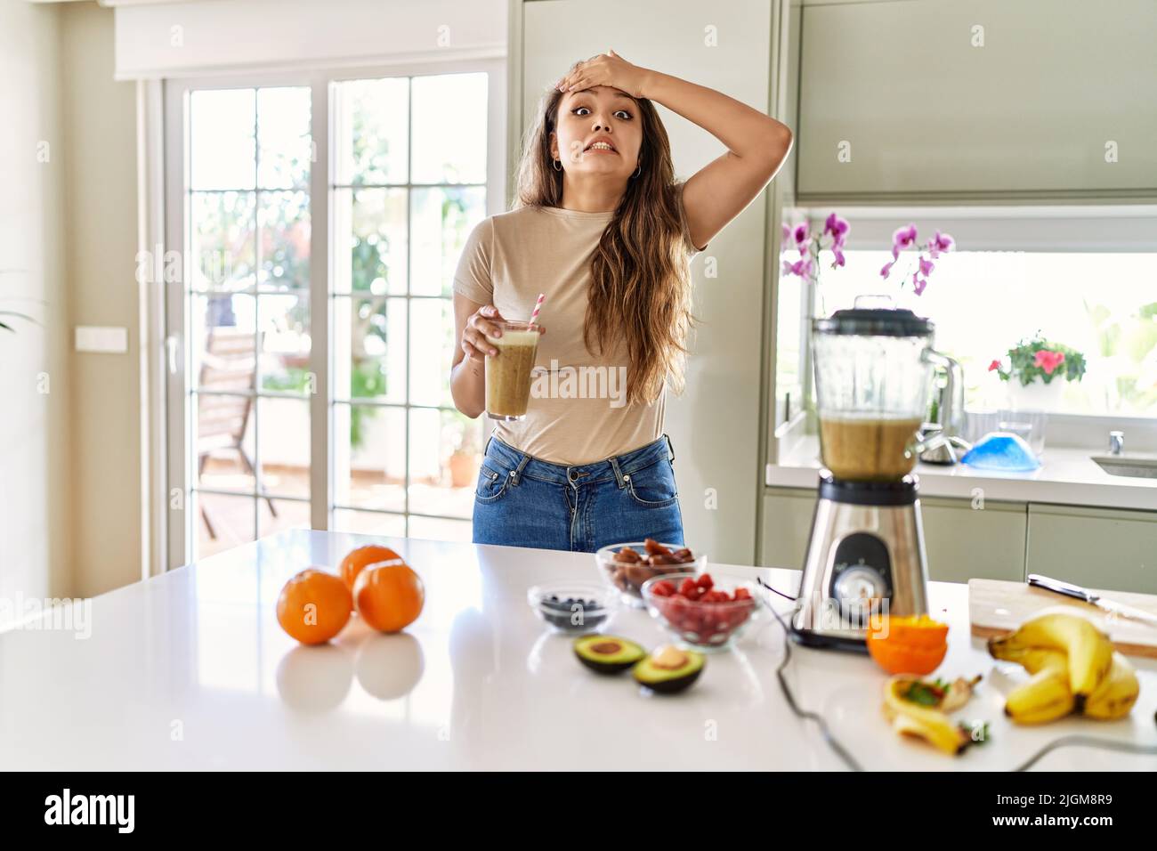 Beautiful young brunette woman drinking glass of smoothie at the ...