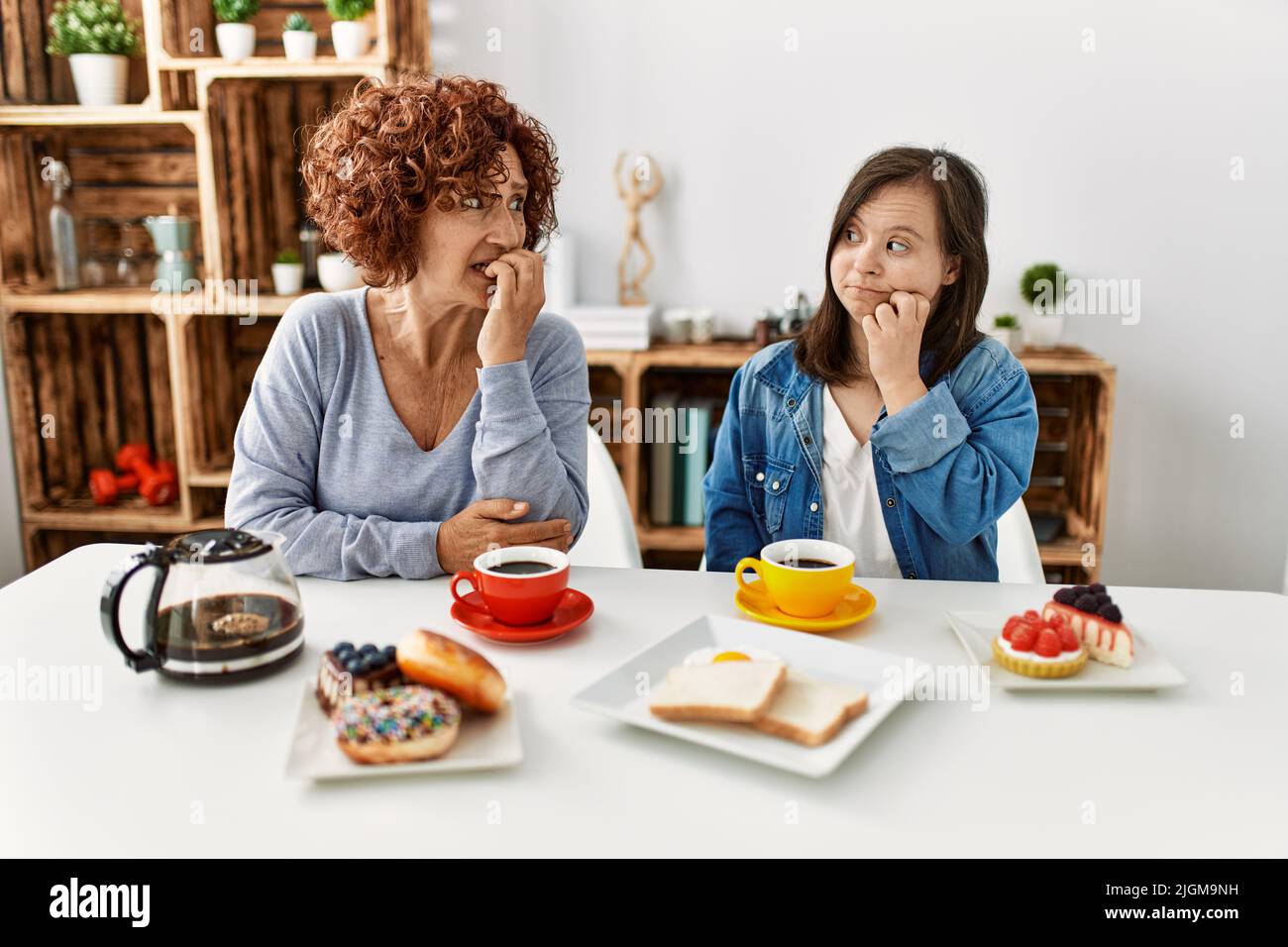 Family of mother and down syndrome daughter sitting at home eating ...