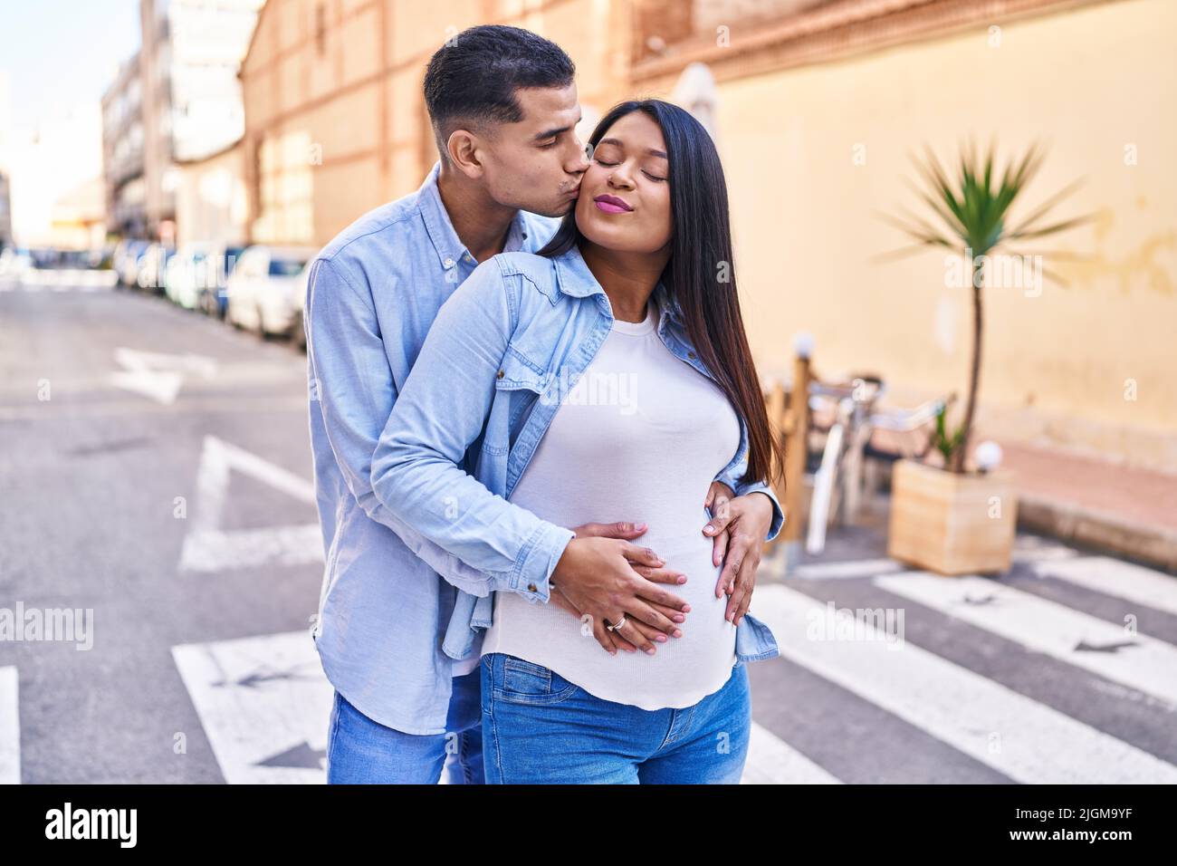 Young latin couple expecting baby hugging each other and kissing at street Stock Photo - Alamy