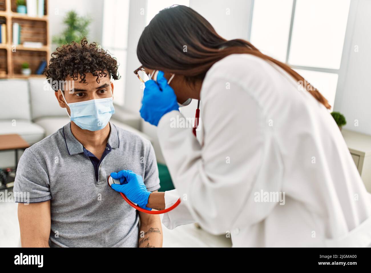 Young latin doctor woman auscultate heart man using stethoscope at ...