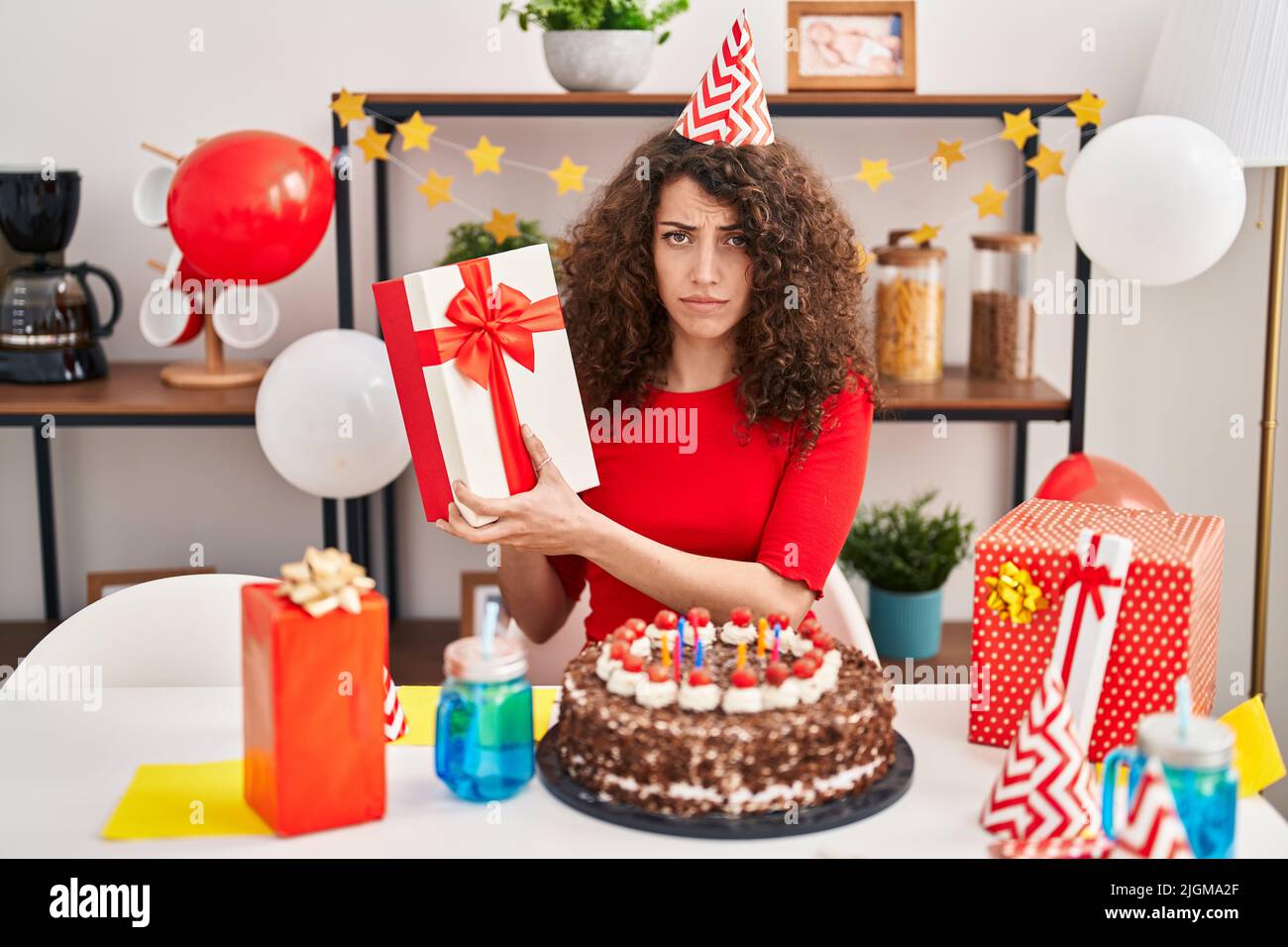 Hispanic woman with curly hair celebrating birthday with cake and ...