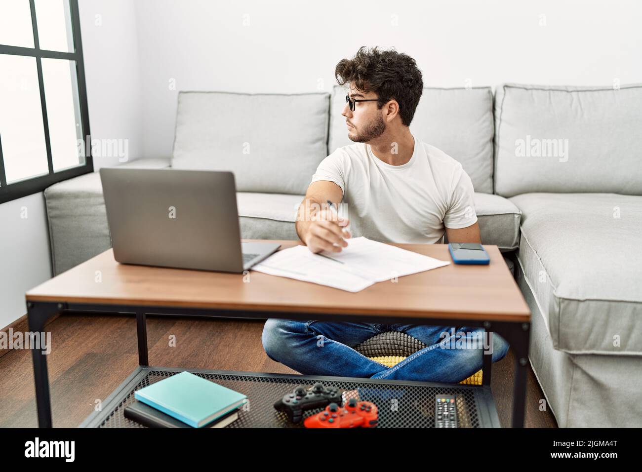 Hispanic man doing papers at home looking to side, relax profile pose ...