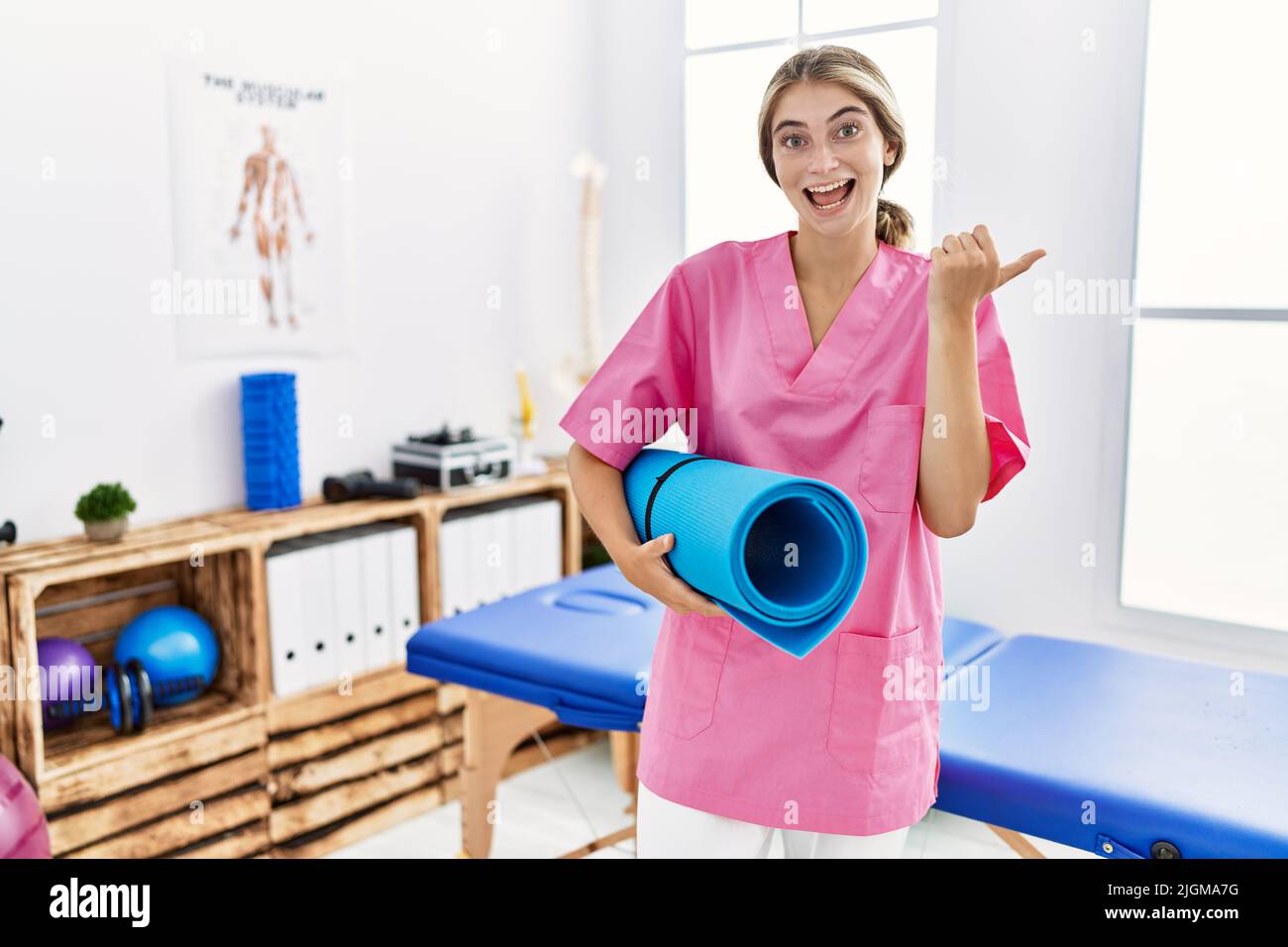Young physiotherapist woman working at pain recovery clinic holding ...