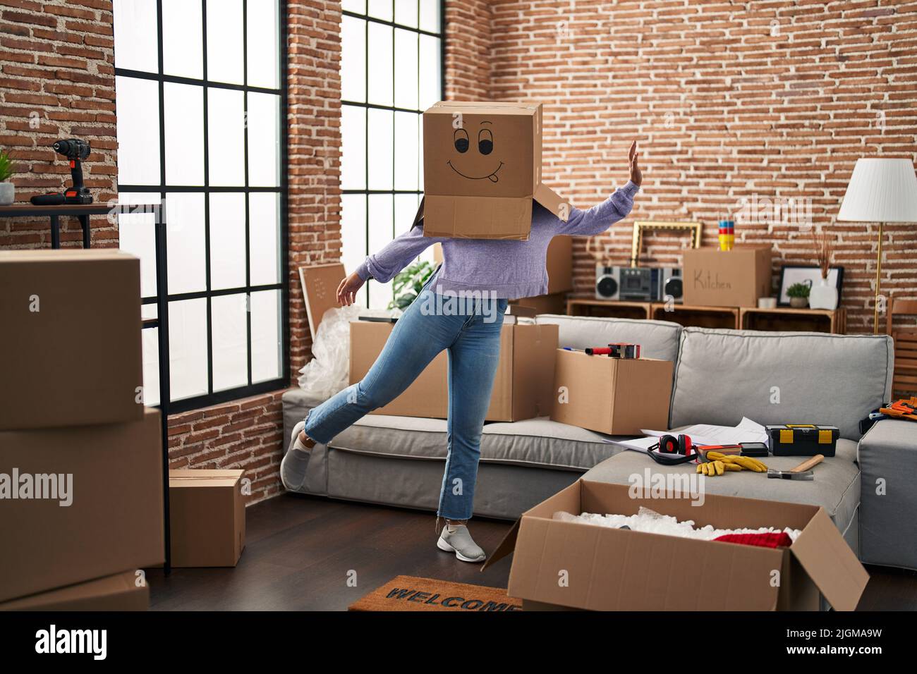 Young african american woman dancing with funny cardboard box on head ...