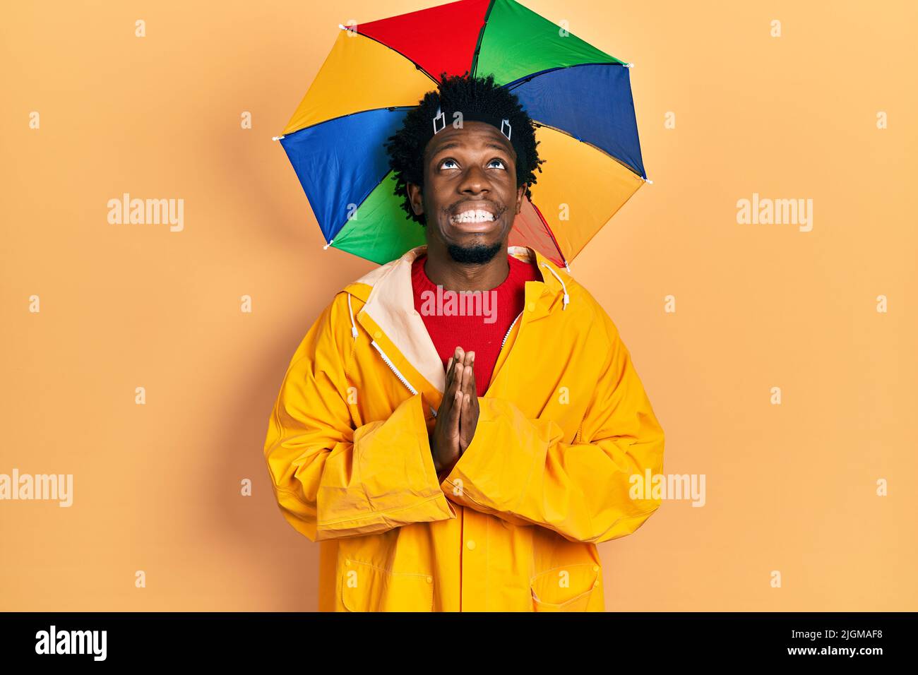Young african american man wearing yellow raincoat begging and praying ...