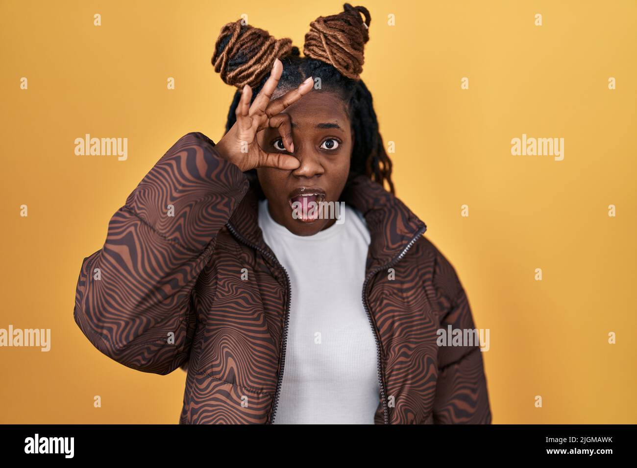 African woman with braided hair standing over yellow background doing ...