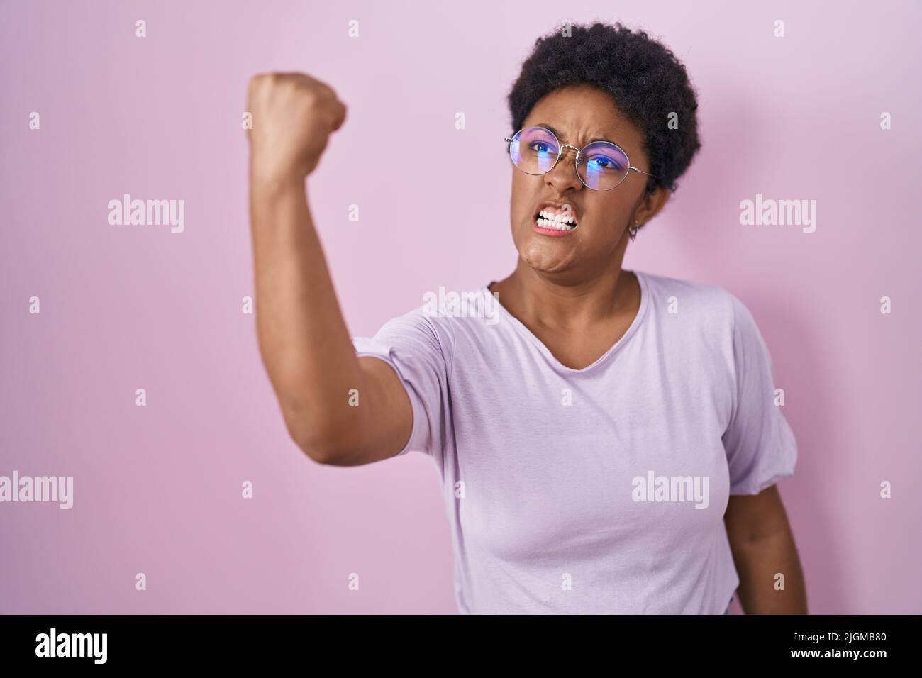 Young african american woman standing over pink background angry and ...