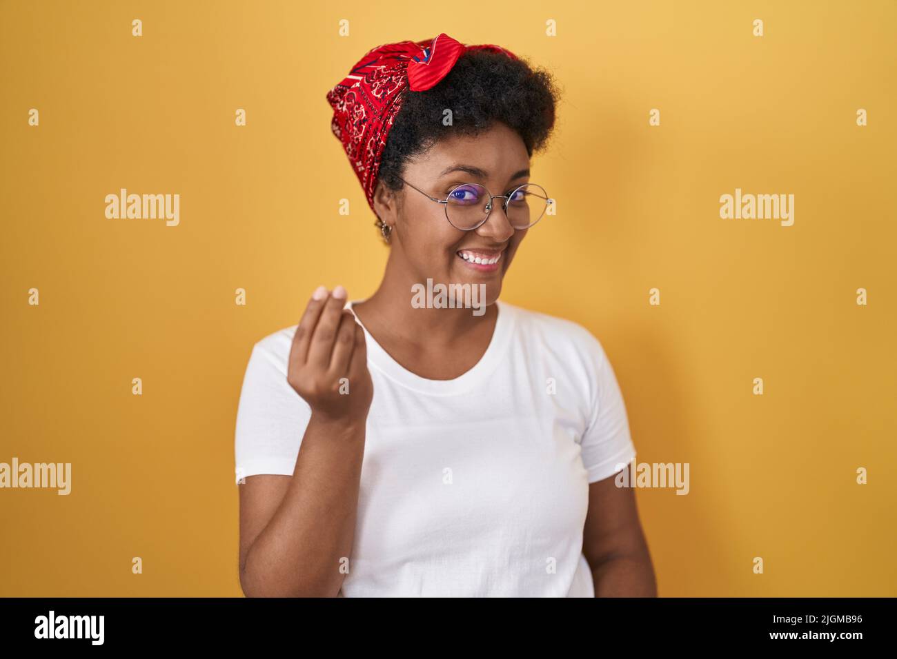 Young african american woman standing over yellow background doing ...