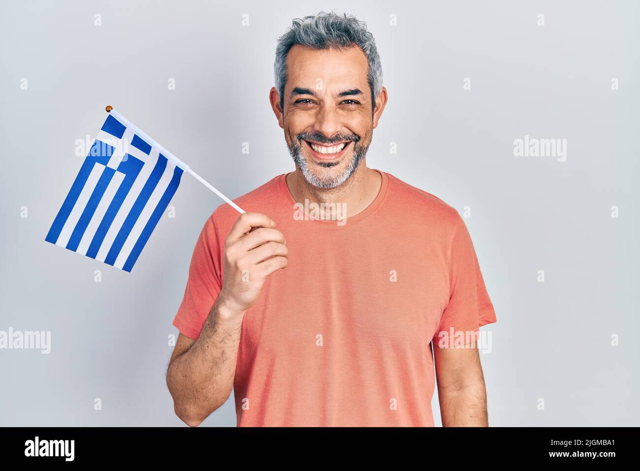 Handsome middle age man with grey hair holding greece flag looking ...