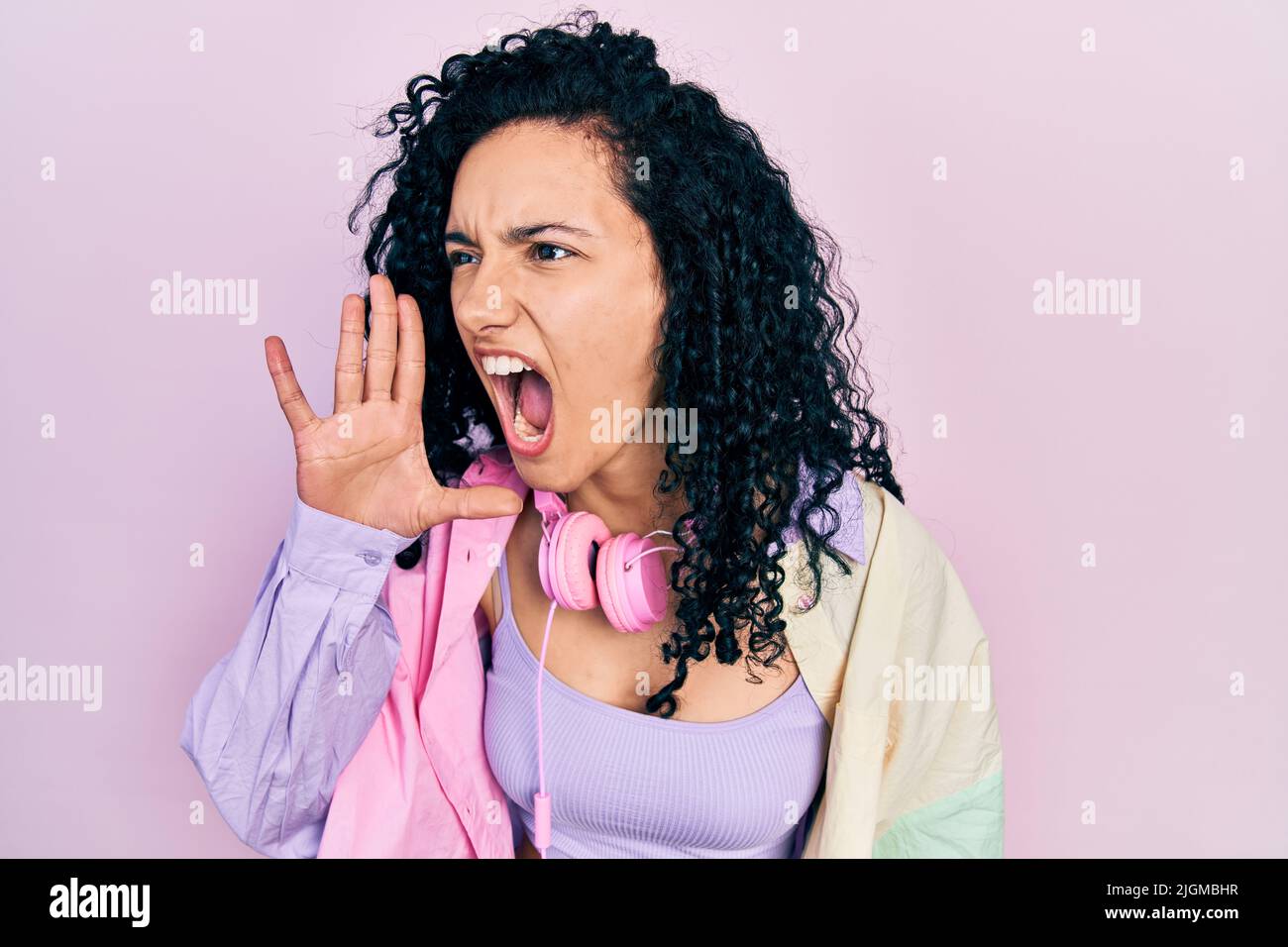 Young hispanic woman with curly hair wearing gym clothes and using ...