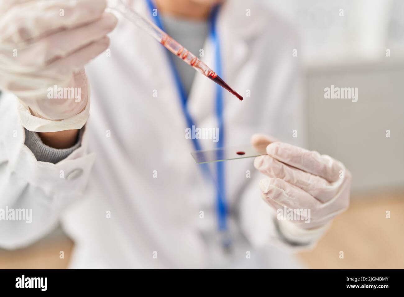 Young blonde woman wearing scientist uniform analysing blood at ...