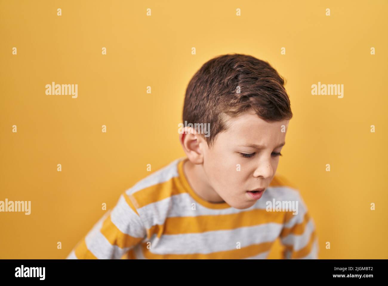 Young caucasian kid standing over yellow background with hand on ...
