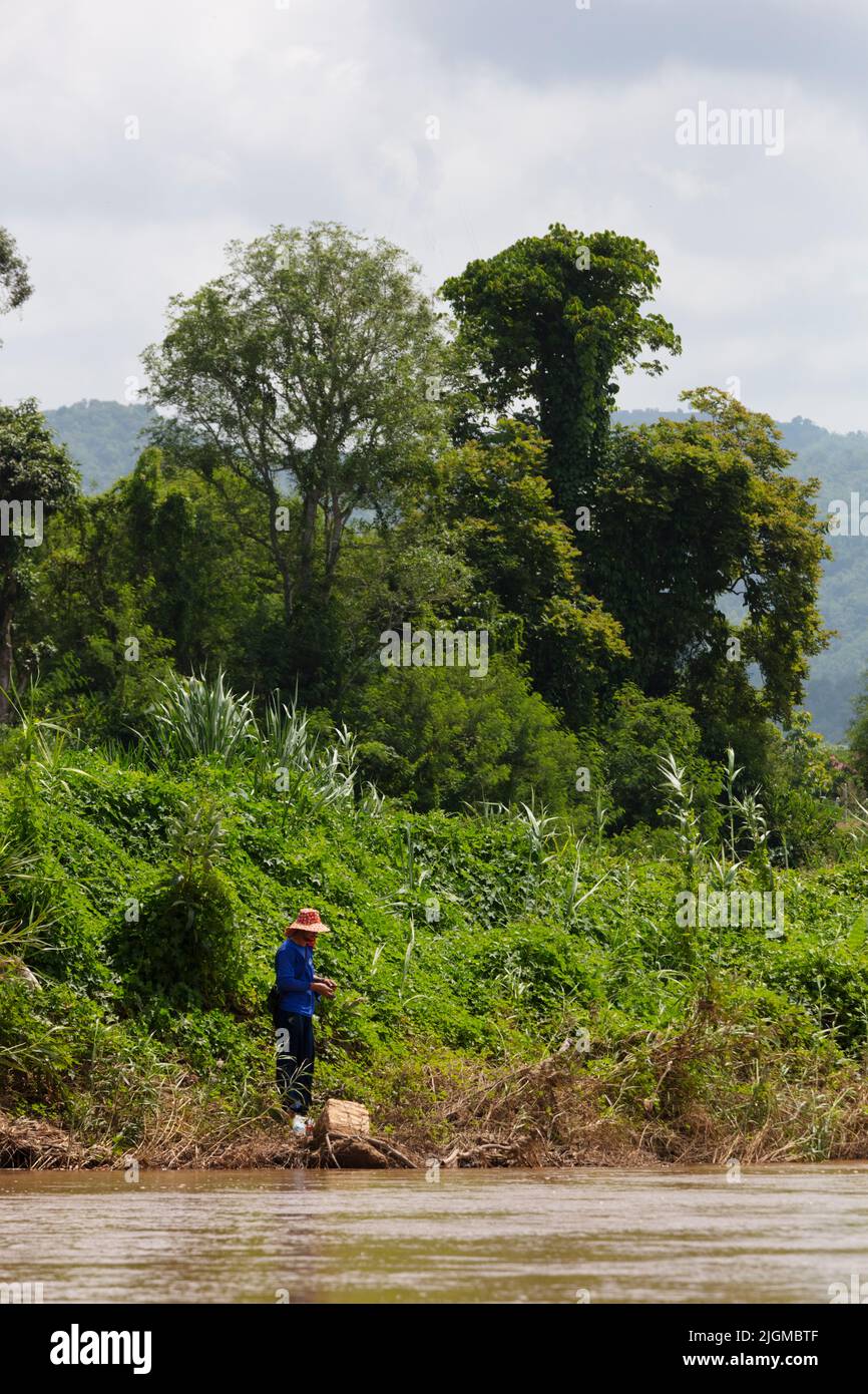 A fisherman on the banks of the MAE KOK RIVER on a boat trip from ...