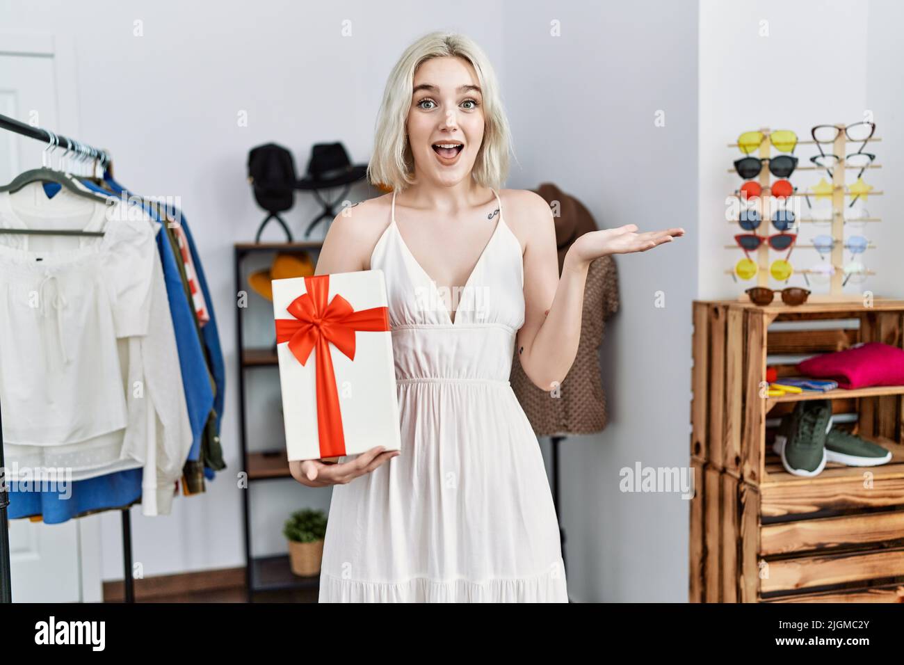 Young caucasian woman holding gift at retail shop celebrating ...