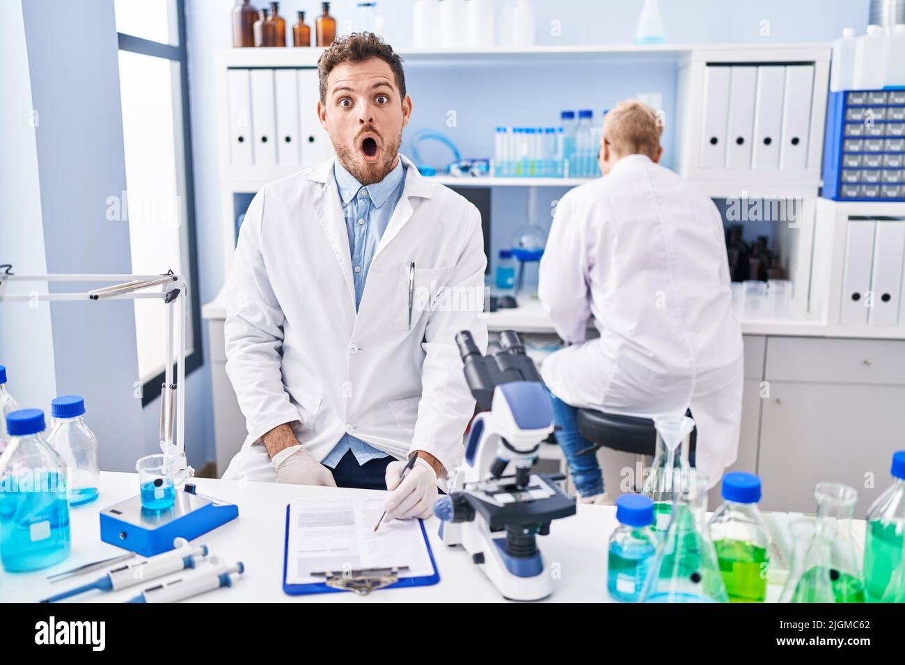 Hispanic man and woman working at scientist laboratory scared and ...