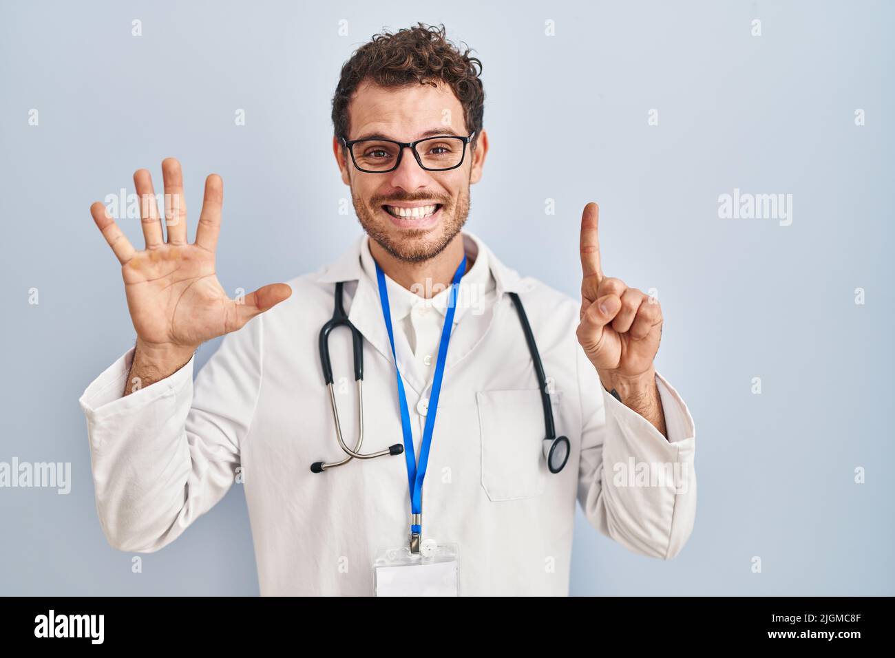 Young hispanic man wearing doctor uniform and stethoscope showing and ...