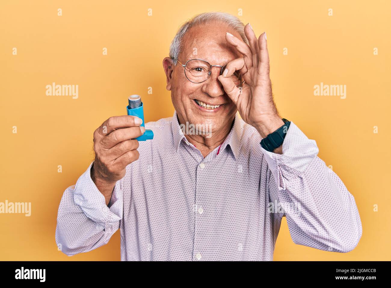 Senior man with grey hair holding medical asthma inhaler smiling happy ...